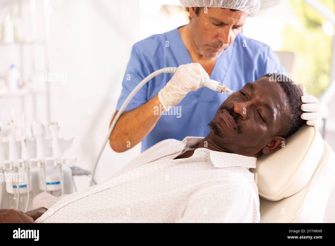 Male cosmetologist performs skin cleansing procedure for African man ...