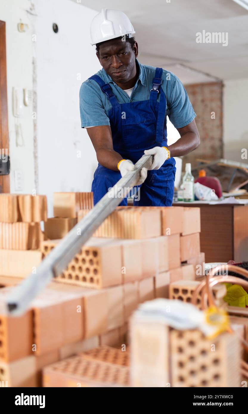 African american builder arranging metal tubes in building under ...