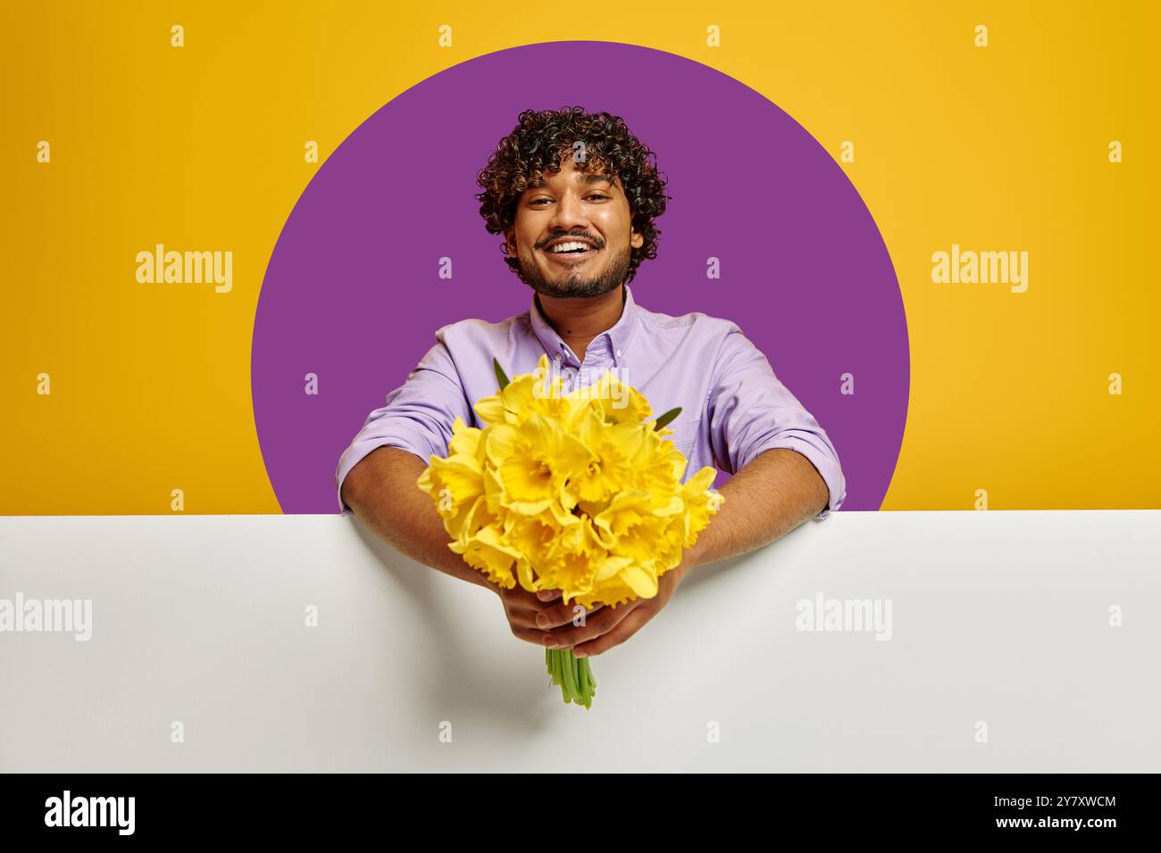 Happy Indian man stretching out flower bouquet against yellow ...