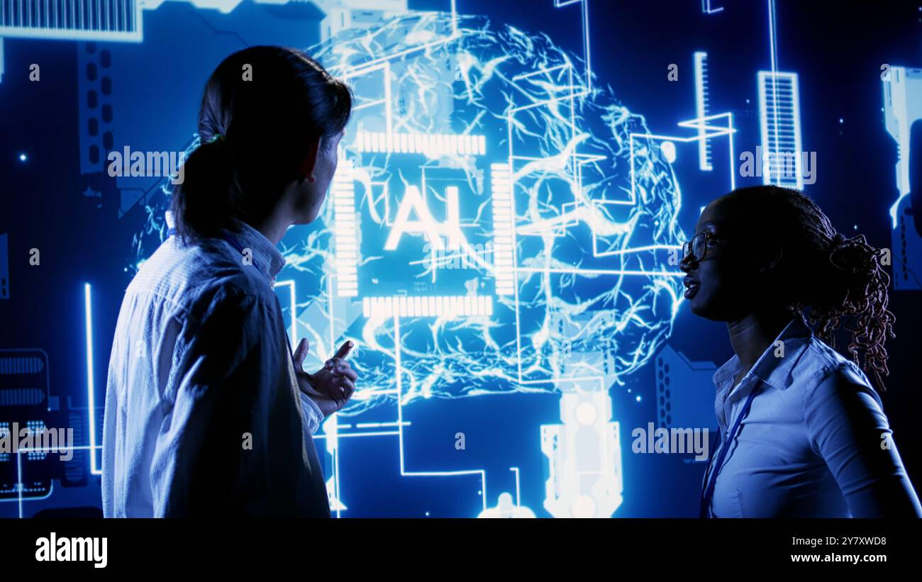 African american engineer and asian coworker looking at hologram of ...