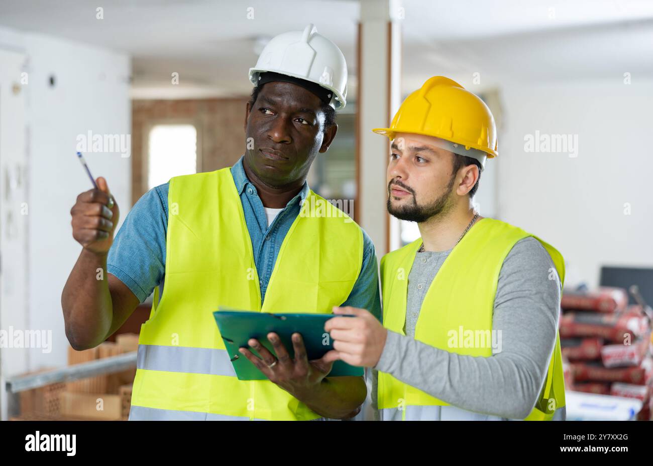 Two builders talking on indoor construction site Stock Photo - Alamy