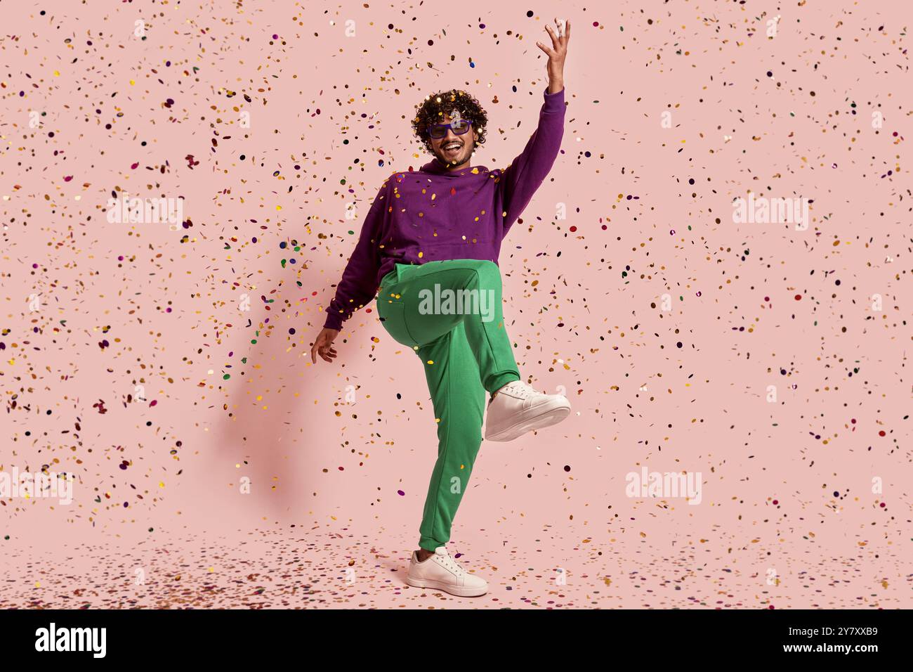 Full length of playful Indian man dancing and throwing confetti against ...