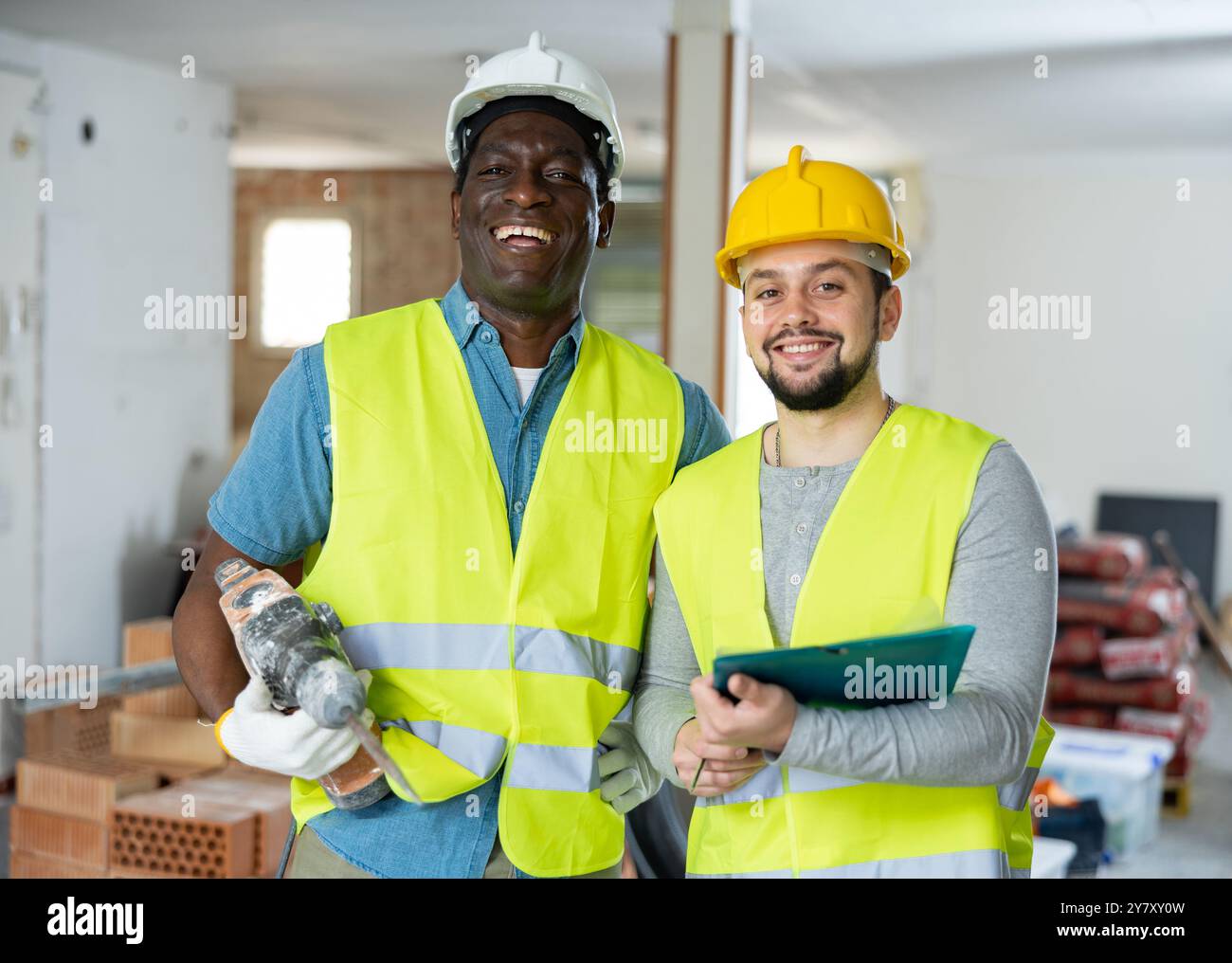 Portrait of two positive builders standing in construction site Stock ...