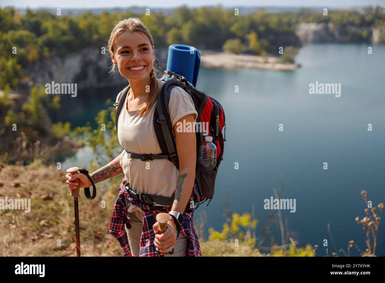 A smiling hiker enjoys breathtaking nature with a backpack and cane ...