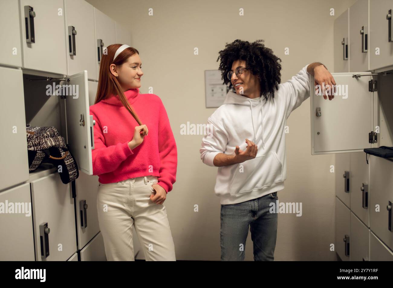 Two young people standing near the lockers and talking Stock Photo - Alamy