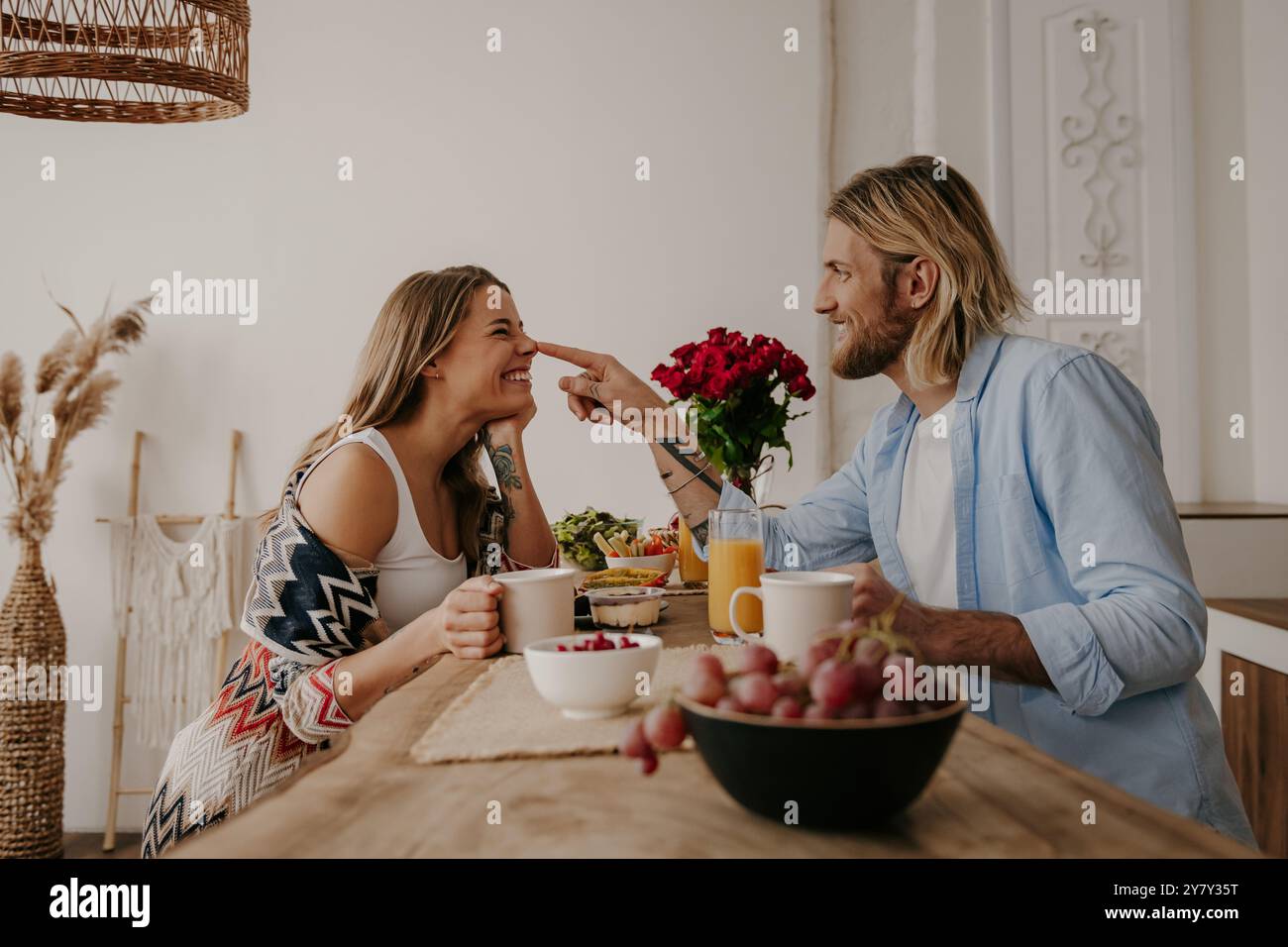 Playful young loving couple enjoying healthy food and drinks while ...