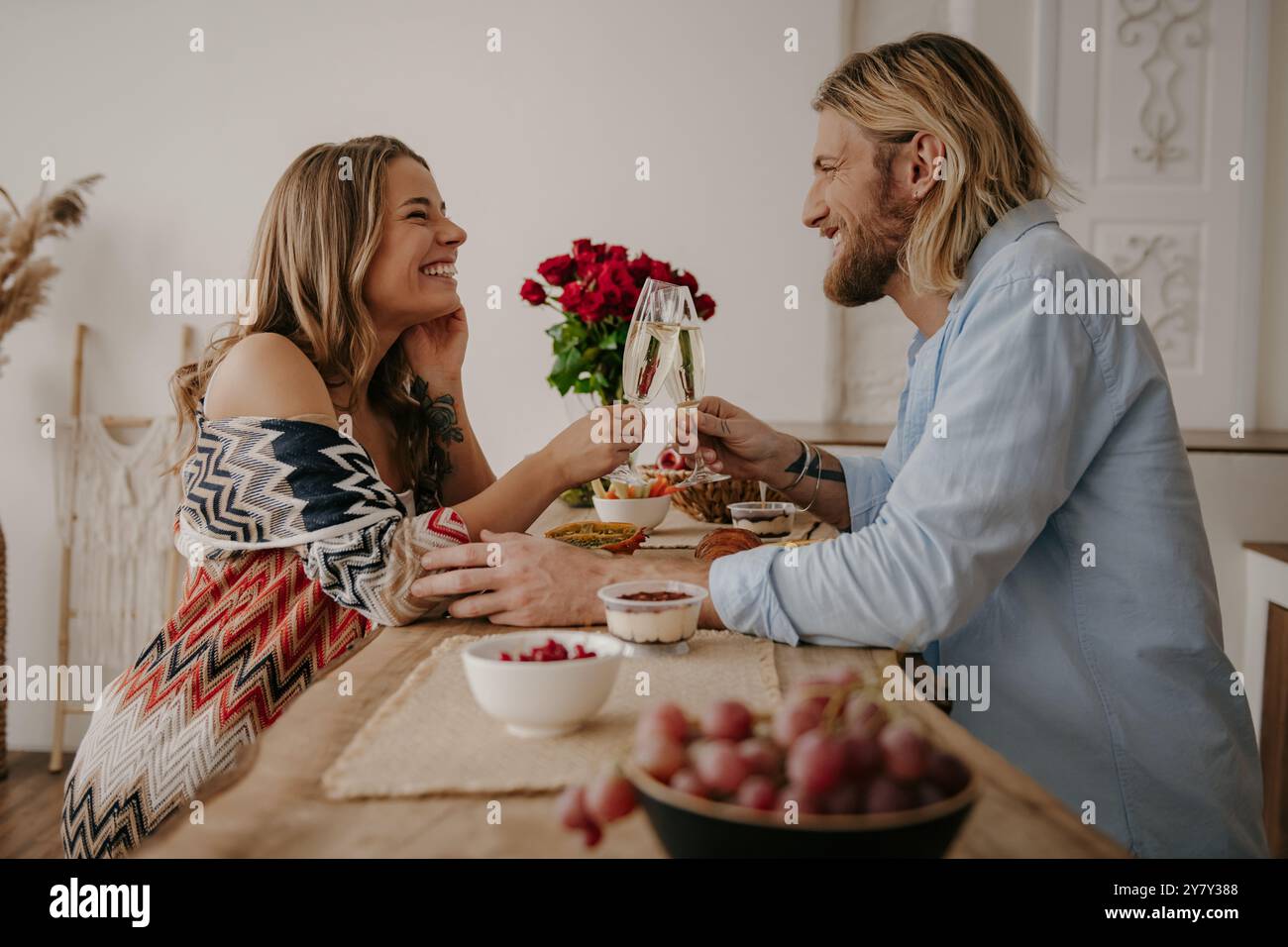 Joyful young loving couple toasting with champagne while celebrating ...