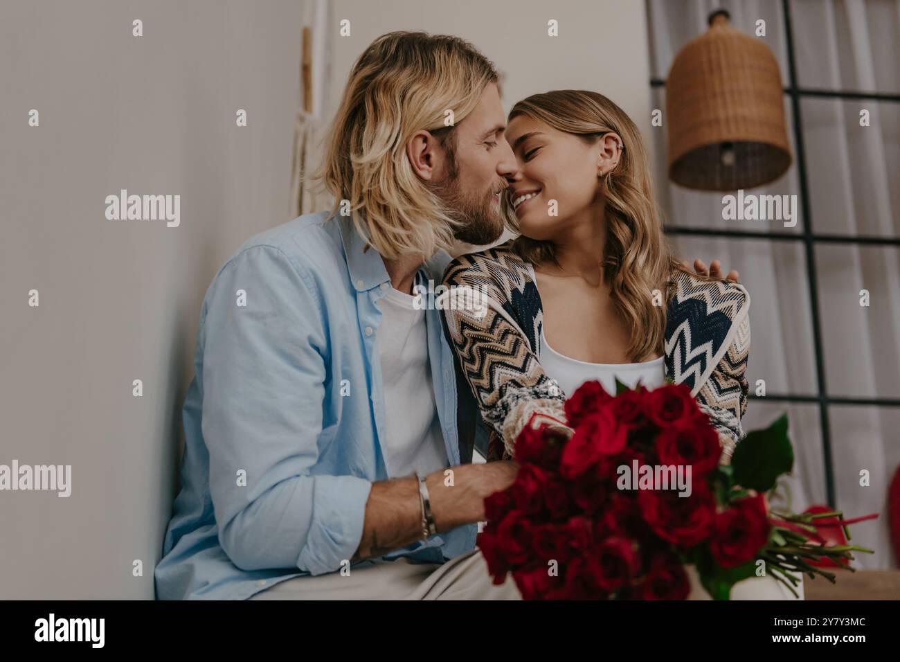 Young romantic couple embracing and kissing at home while woman holding ...