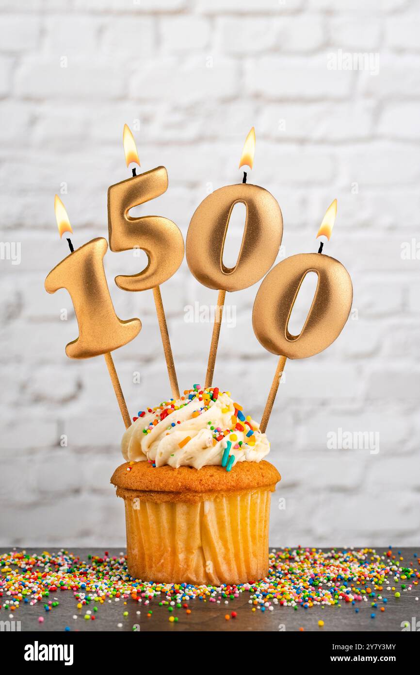 Cupcake with number 1500 birthday candle - White block wall background ...