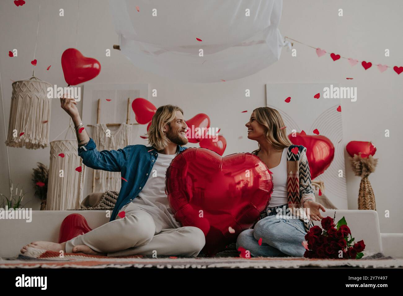 Happy loving couple holding big red heart shape balloon and throwing ...