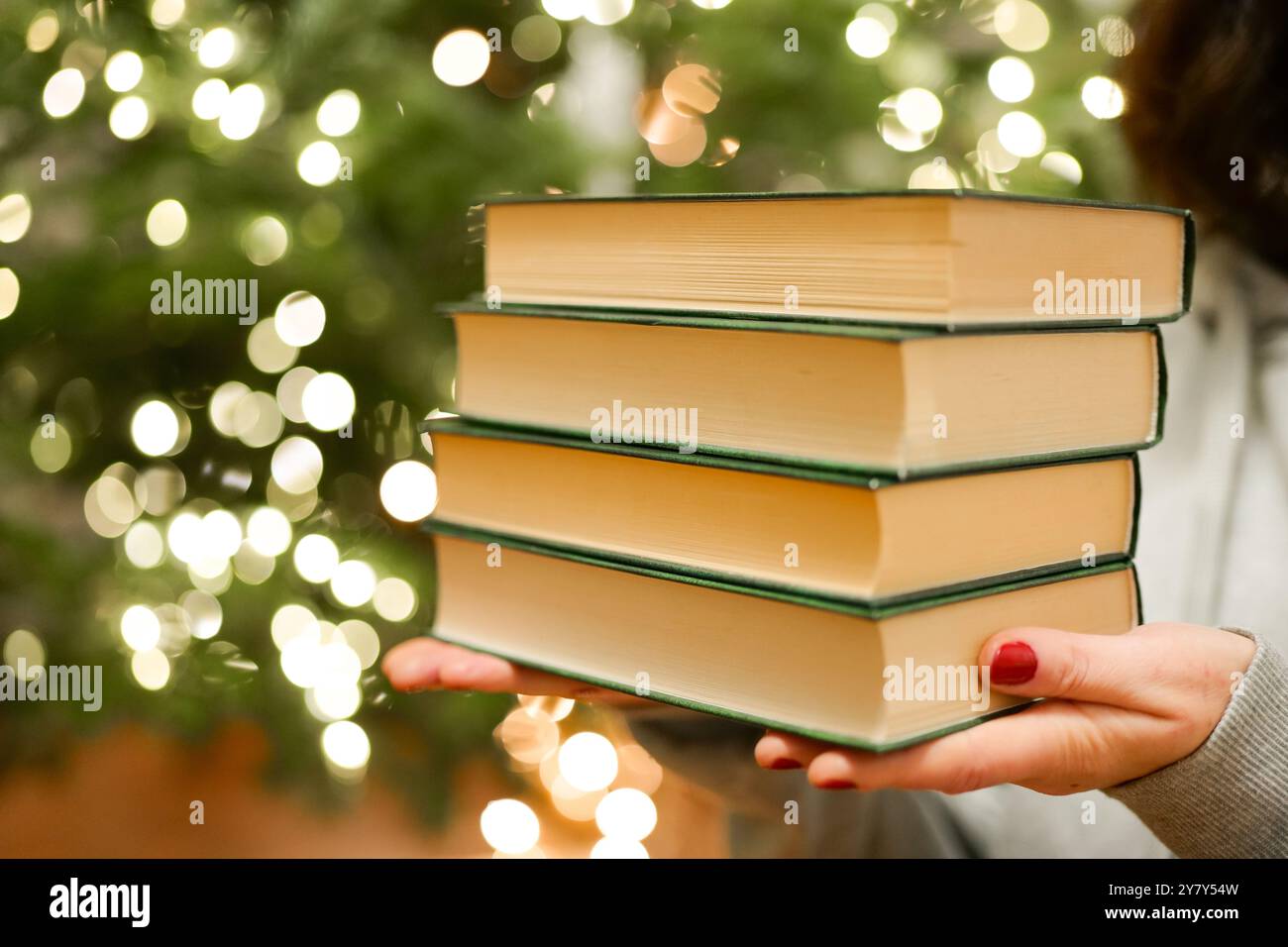 stack of books on Christmas shining tree background. Hands holding ...