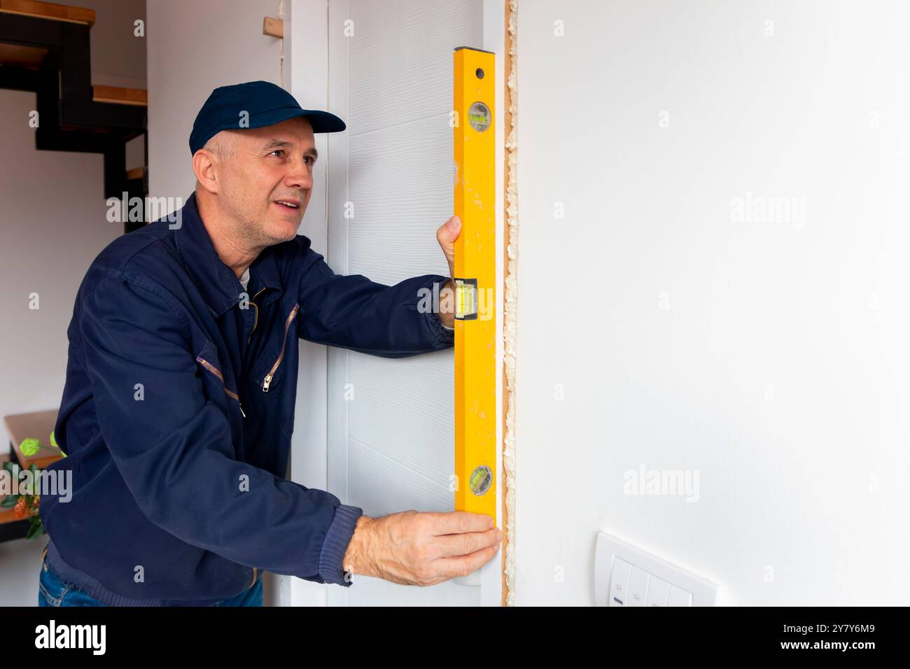 A worker's hands with spirit level against frame of the door. An ...