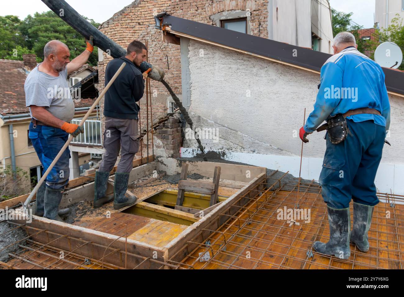 Construction workers pour concrete on rebar using concrete pump ...