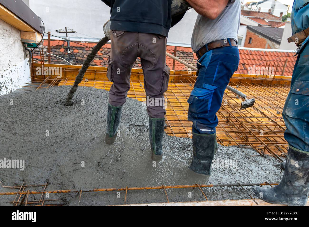 Construction workers pour concrete on rebar using concrete pump ...