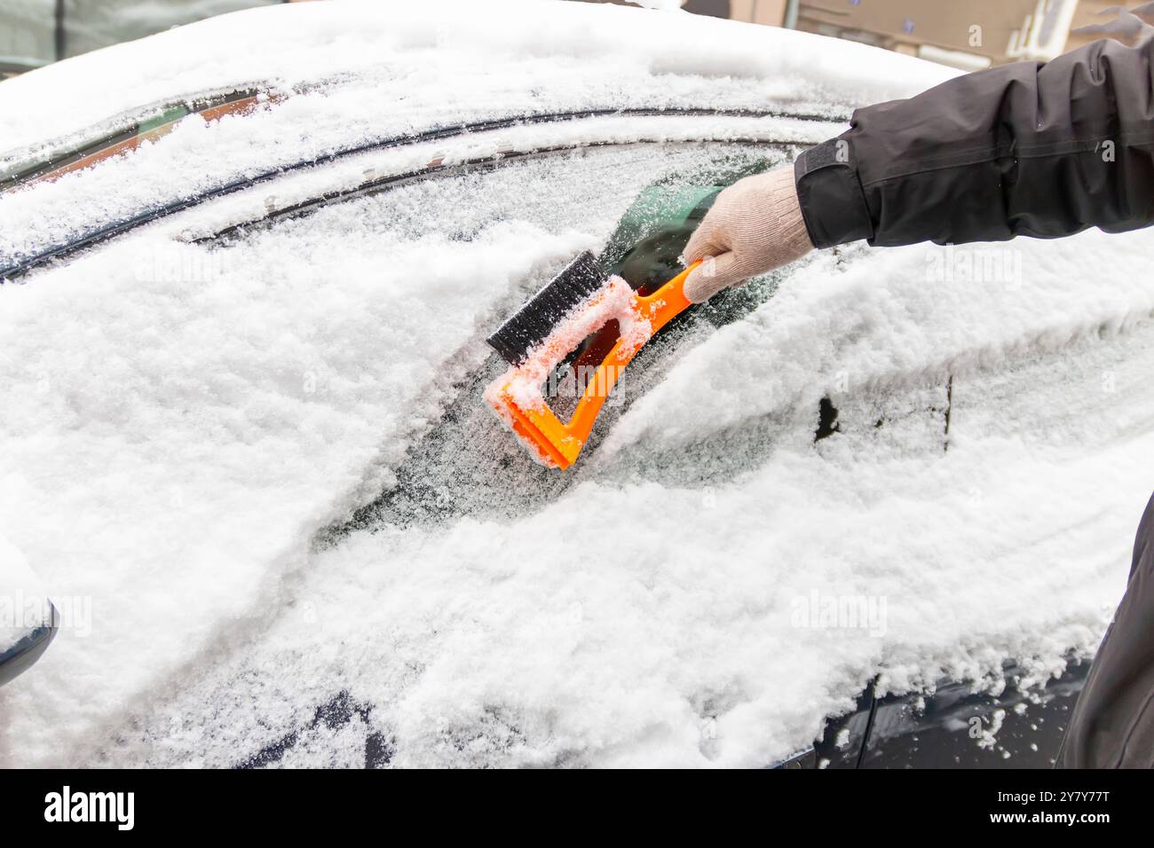 Winter season driving. Close-up of a hand cleaning a vehicle's ...