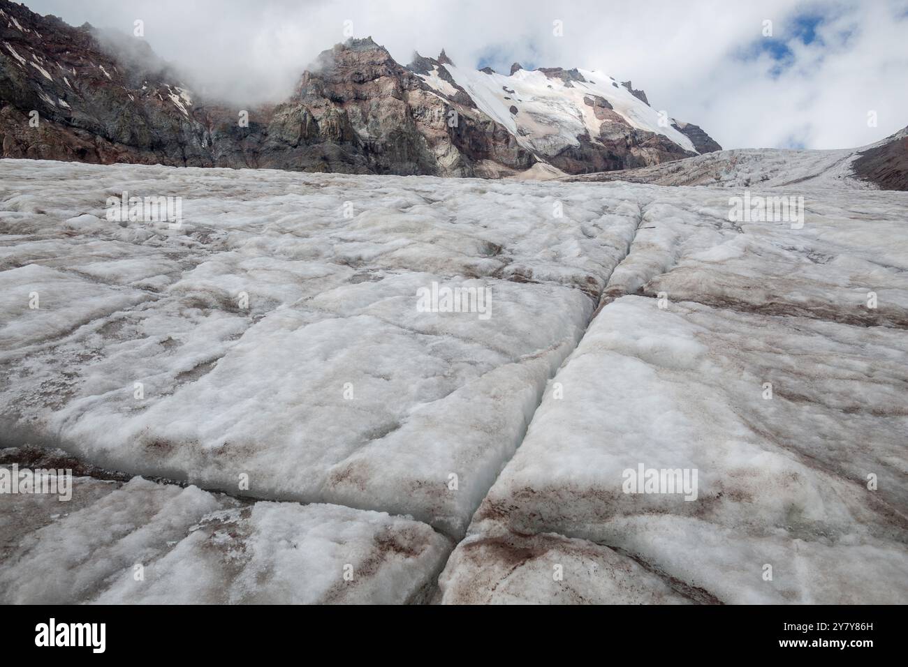 The icy expanse of a glacier contrasts with the rugged mountain peaks ...