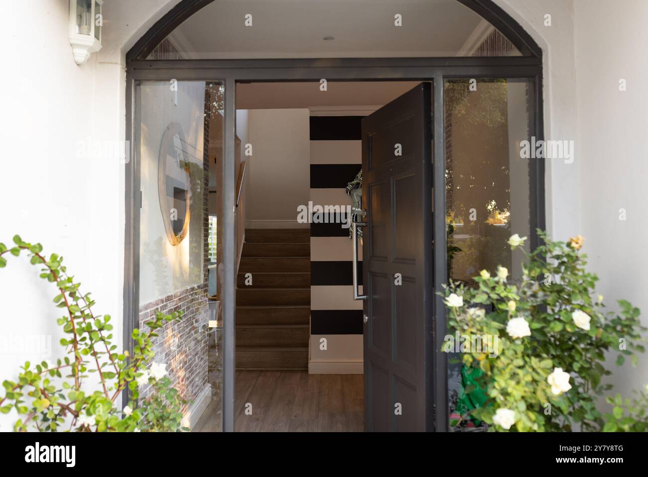 Outdoors, Open front door of modern home with plants and staircase in view, copy space Stock ...
