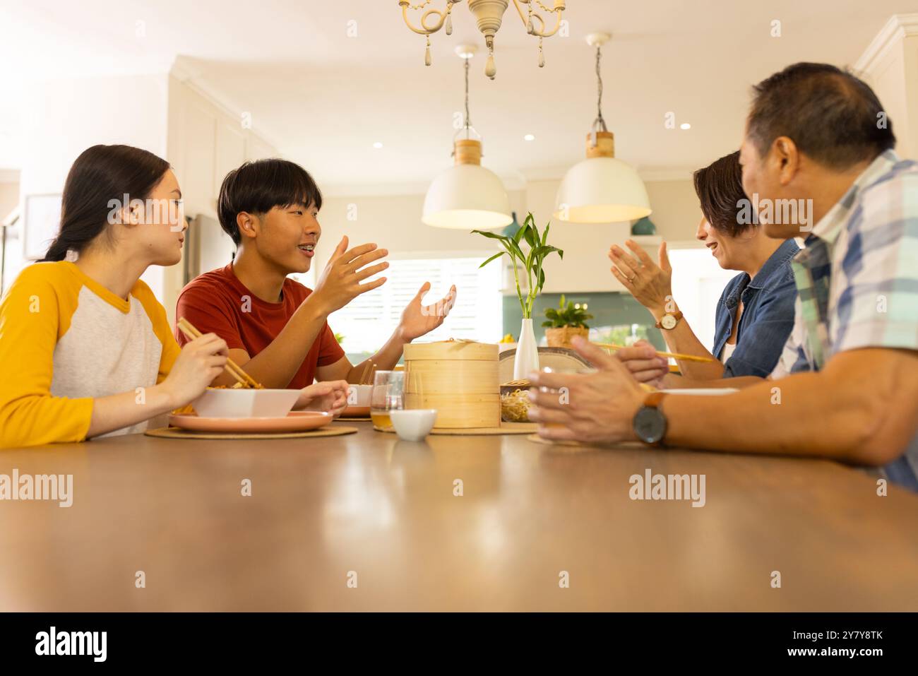 At home, asian family enjoying meal together, talking and laughing ...