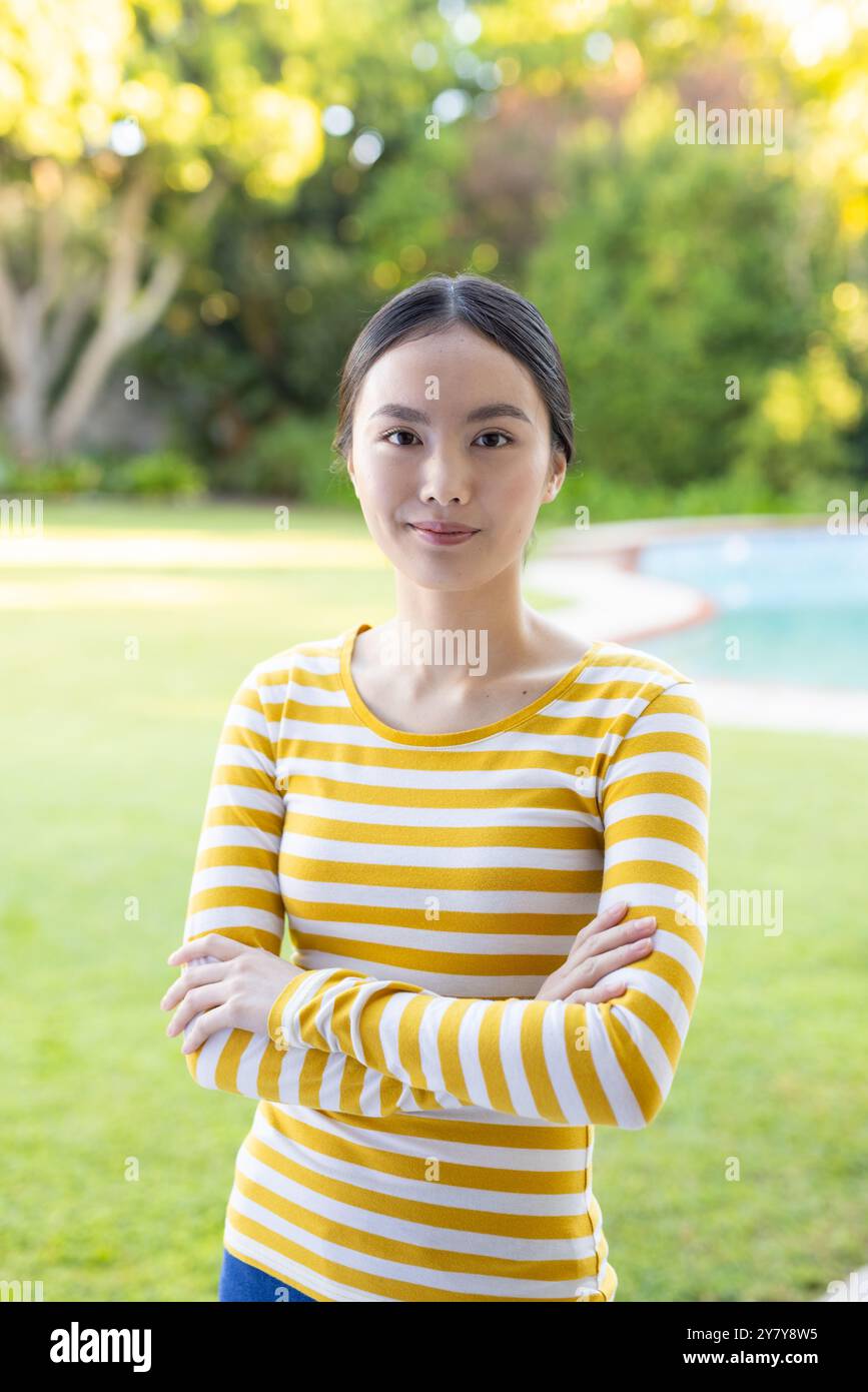Outdoors, Smiling young asian woman in yellow striped shirt standing ...