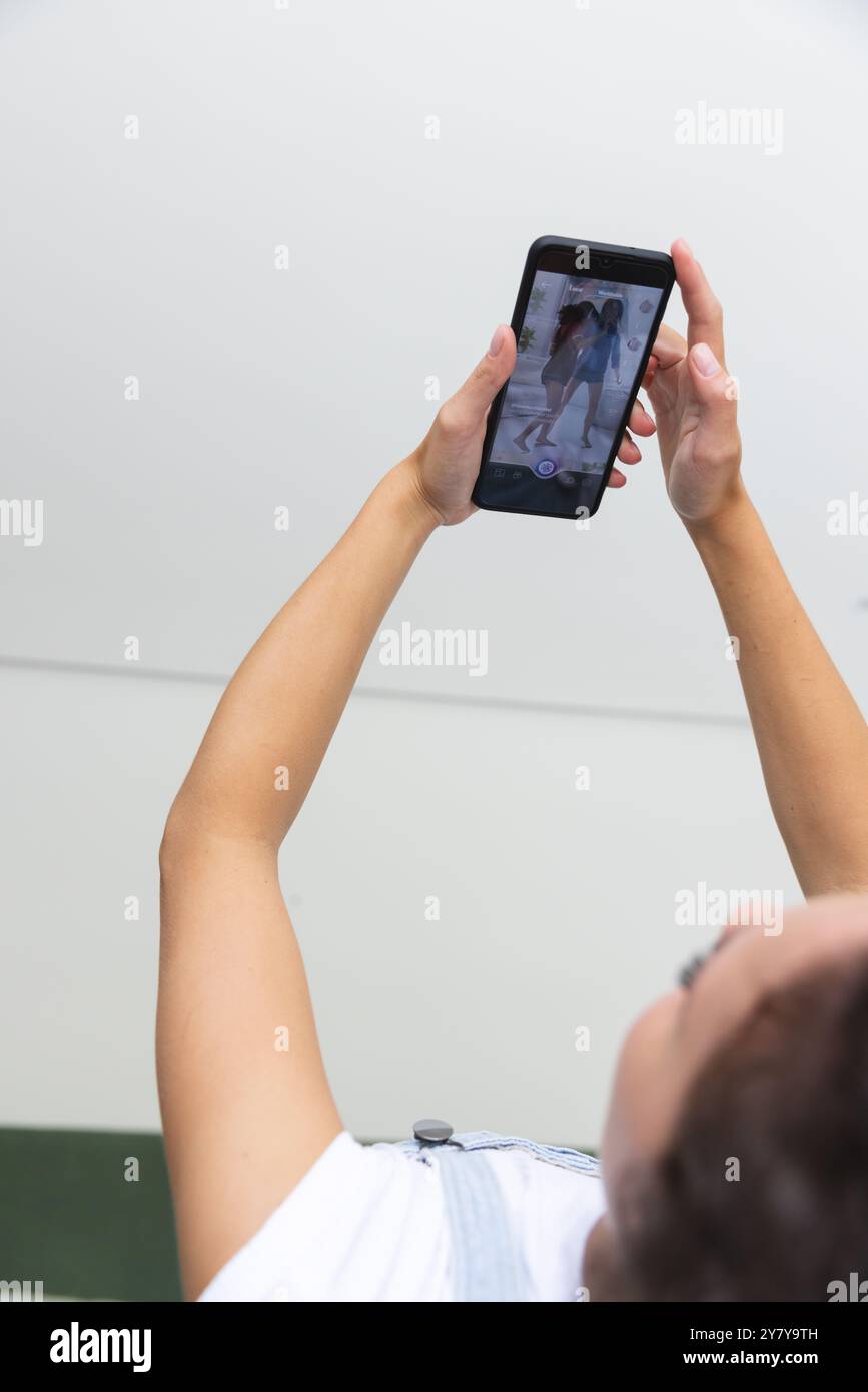 Holding smartphone, woman watching video of people dancing inside room ...