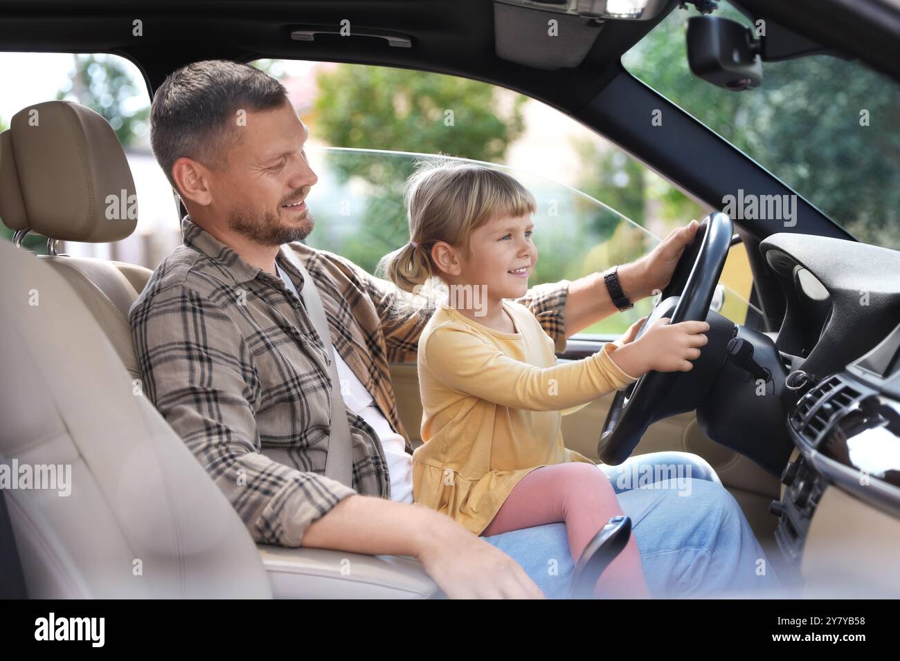 Man with his daughter holding steering wheel inside car Stock Photo - Alamy