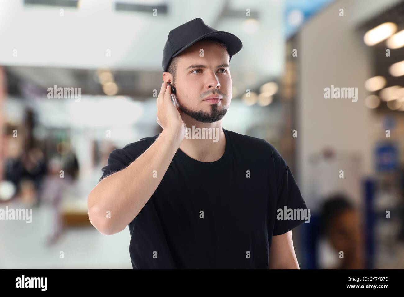 Confident security guard with earpiece in shopping mall Stock Photo - Alamy