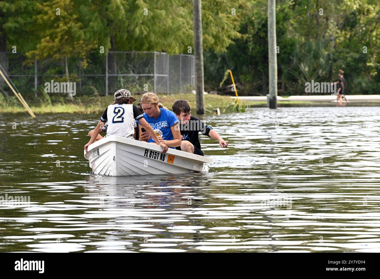 Children make their way through a flooded neighborhood street on a ...