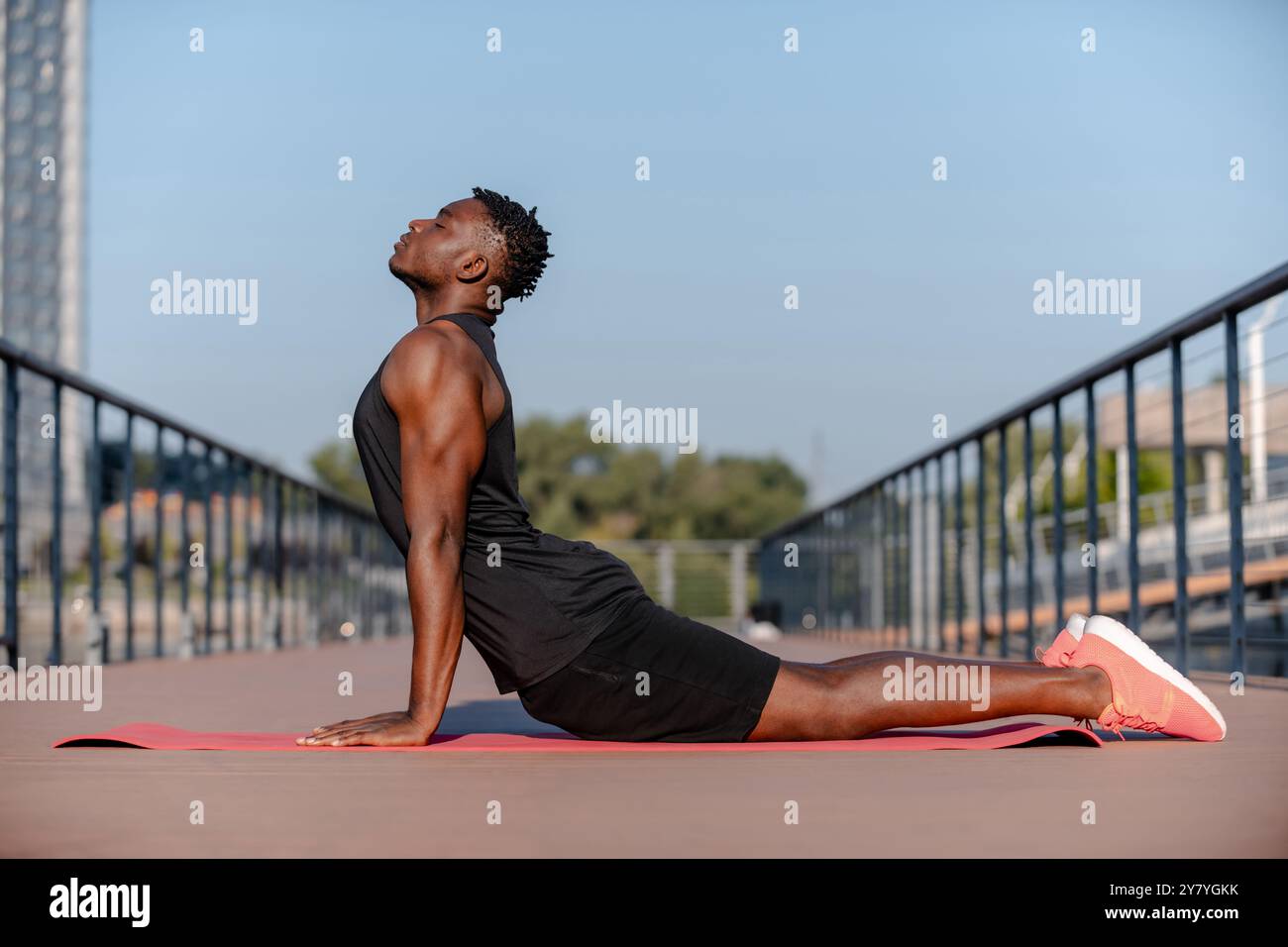 Confident young African man in sportswear doing stretching exercises ...