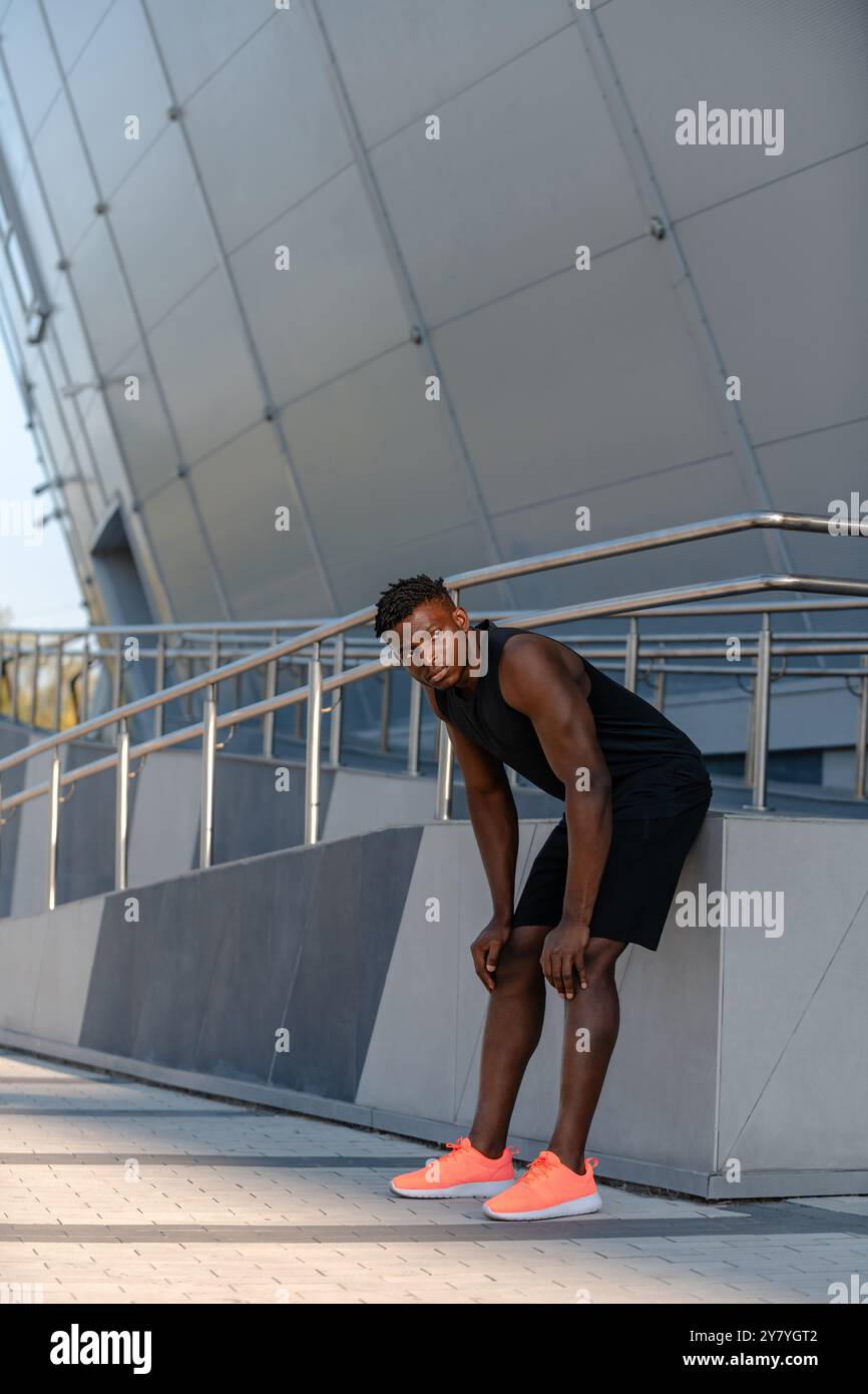 Tired African man in sportswear leaning hands on knees while resting ...