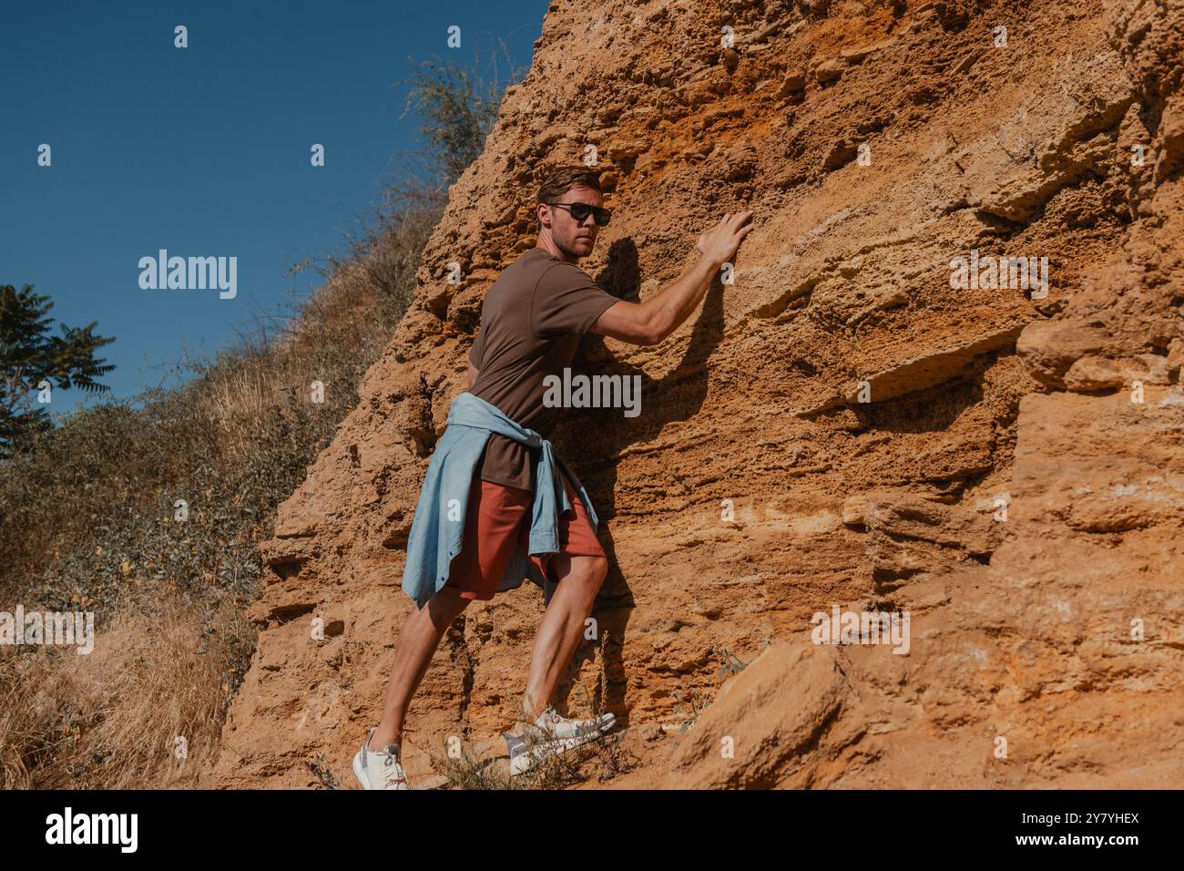 Confident male adventurer holding on grip while climbing the rock as ...