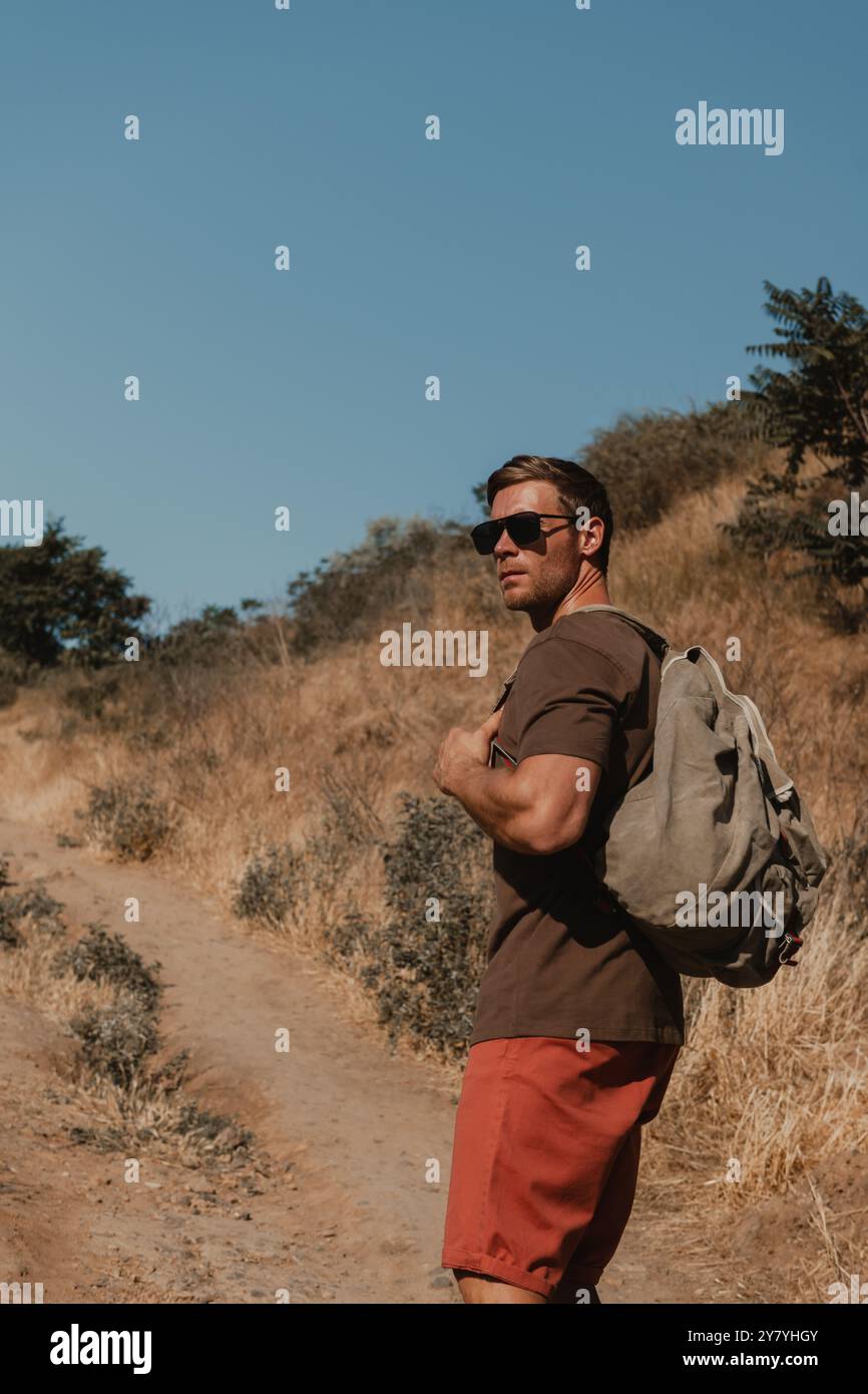 Confident male adventurer with backpack walking by the mountain ...