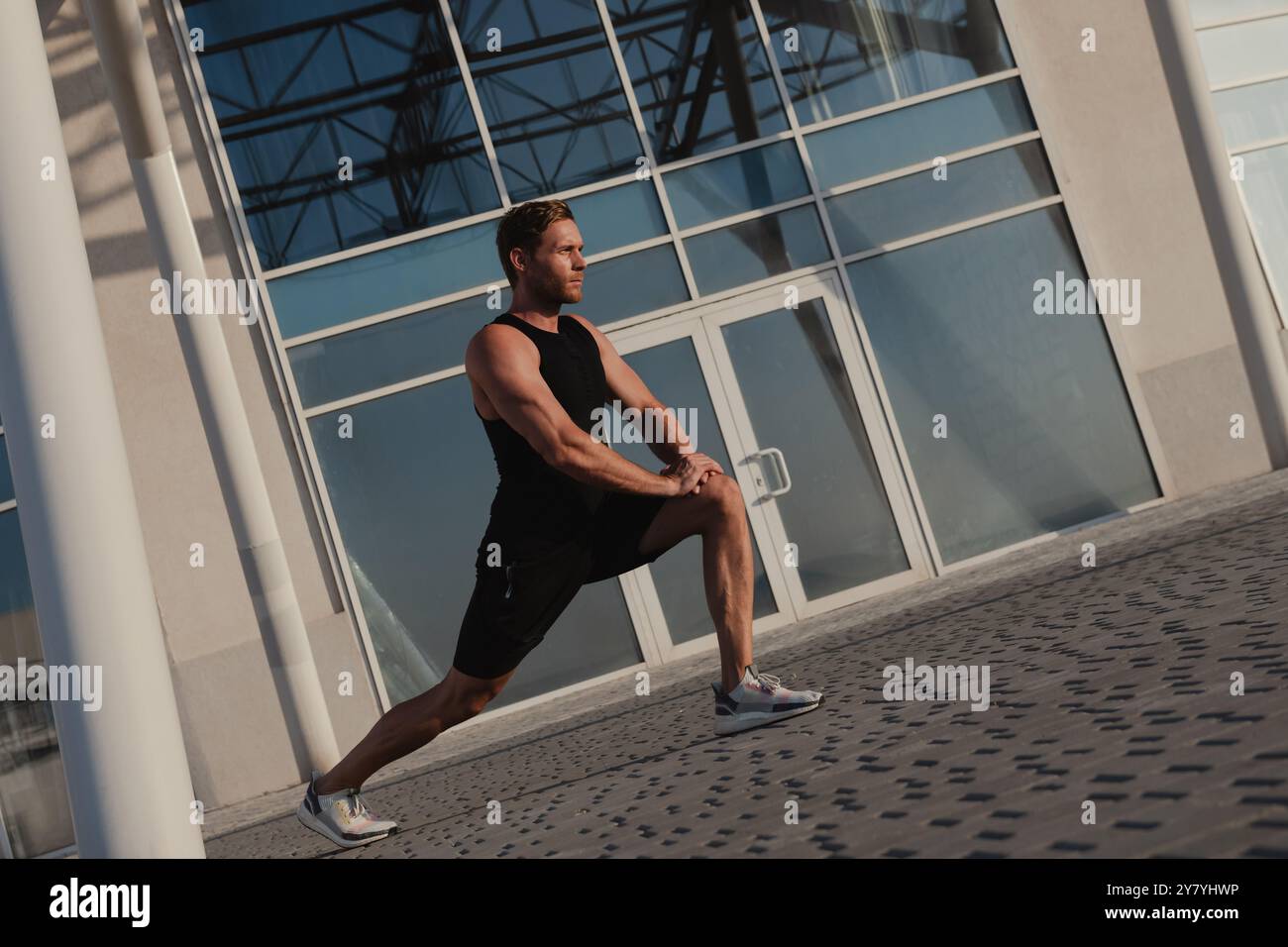 Confidant male athlete doing stretching exercises outdoors against ...