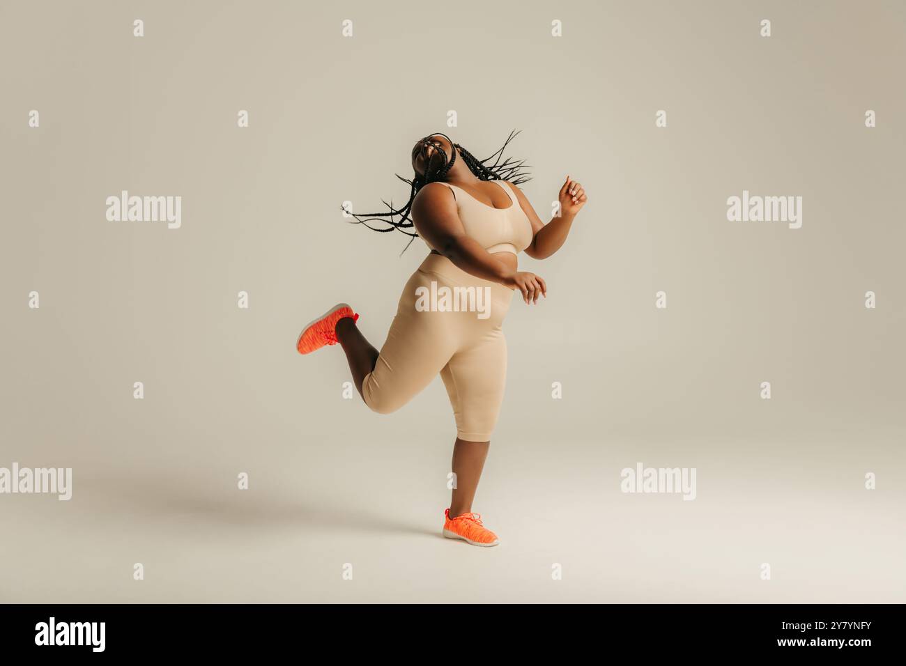 Full length of happy curvy African woman in sportswear dancing on ...