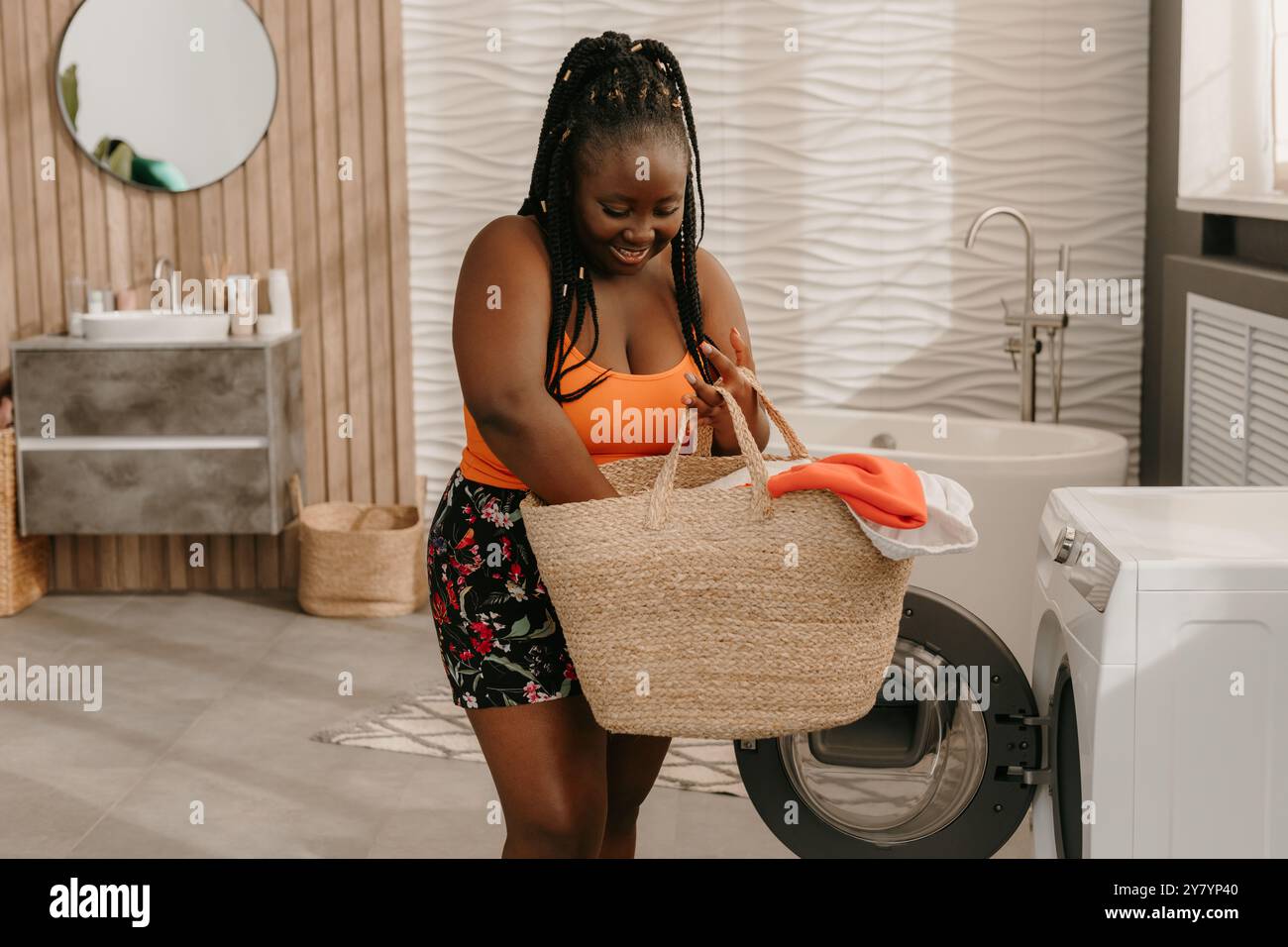Beautiful curvy African woman loading clothes into washing machine ...
