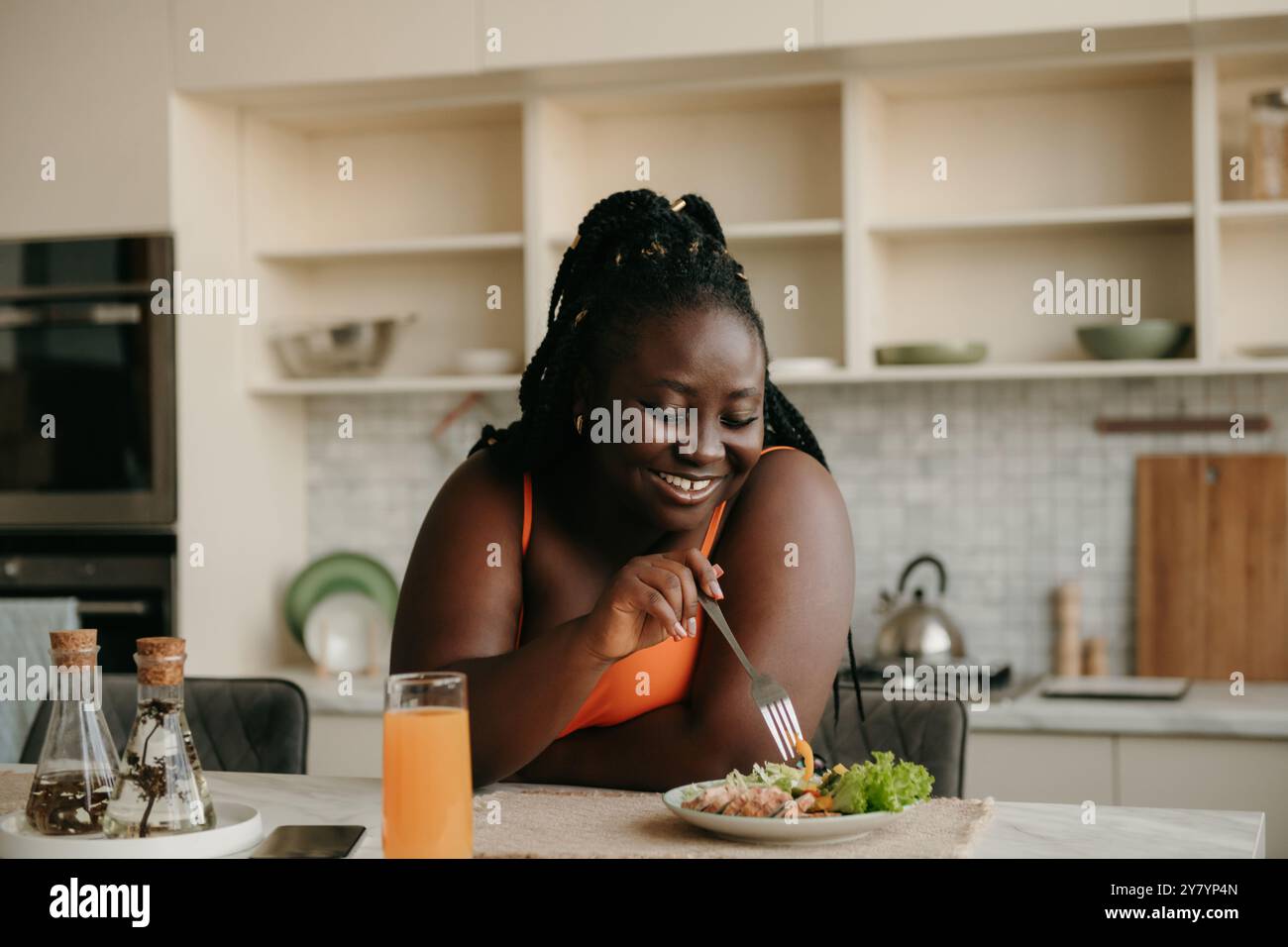 Beautiful curvy African woman enjoying healthy eating for lunch at home ...