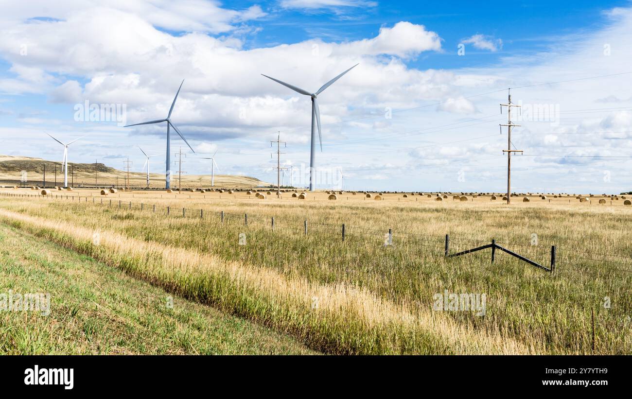 Wind power towers turbines on agricultural field with bales of hay at ...