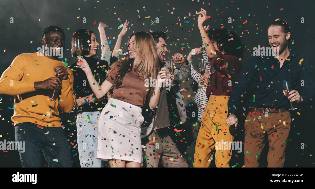 Group of joyful young people dancing and throwing confetti while ...