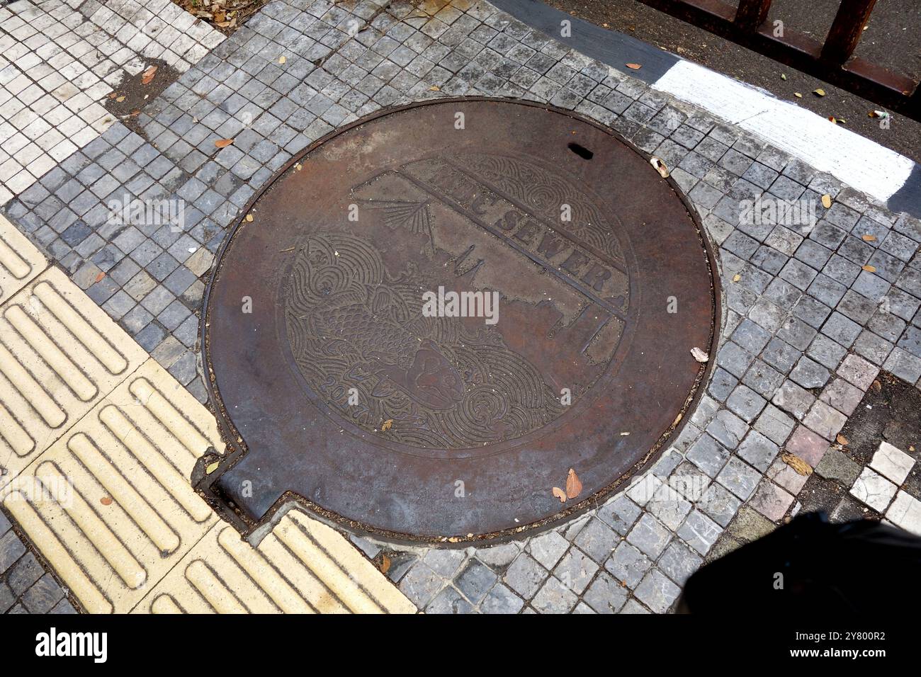 Manhole cover over sewer featuring a coelacanth fish, Manado, Sulawesi ...