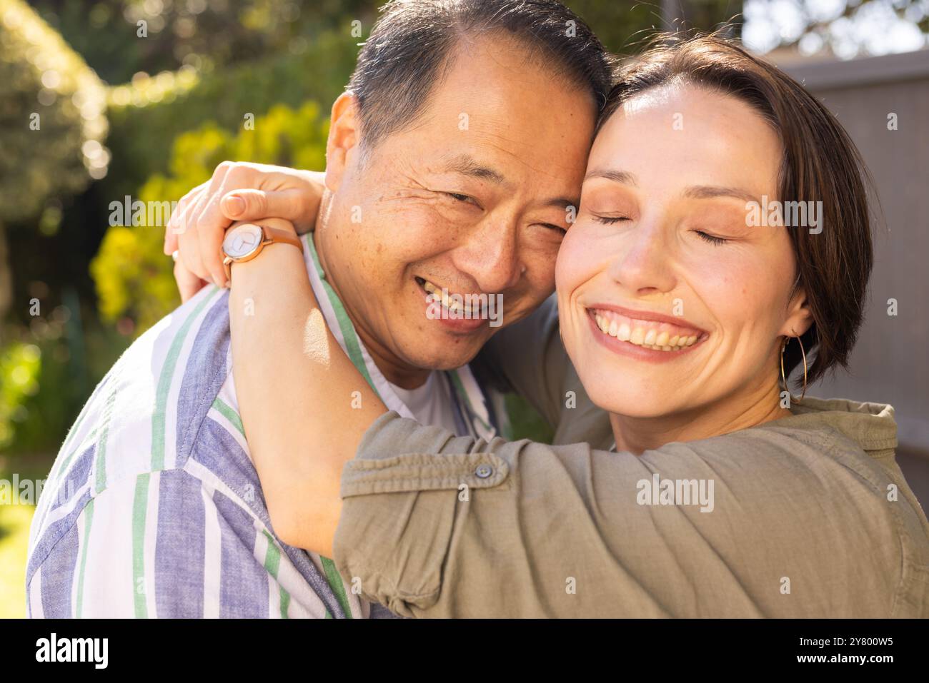 Smiling multiracial middle-aged couple embracing outdoors, enjoying ...