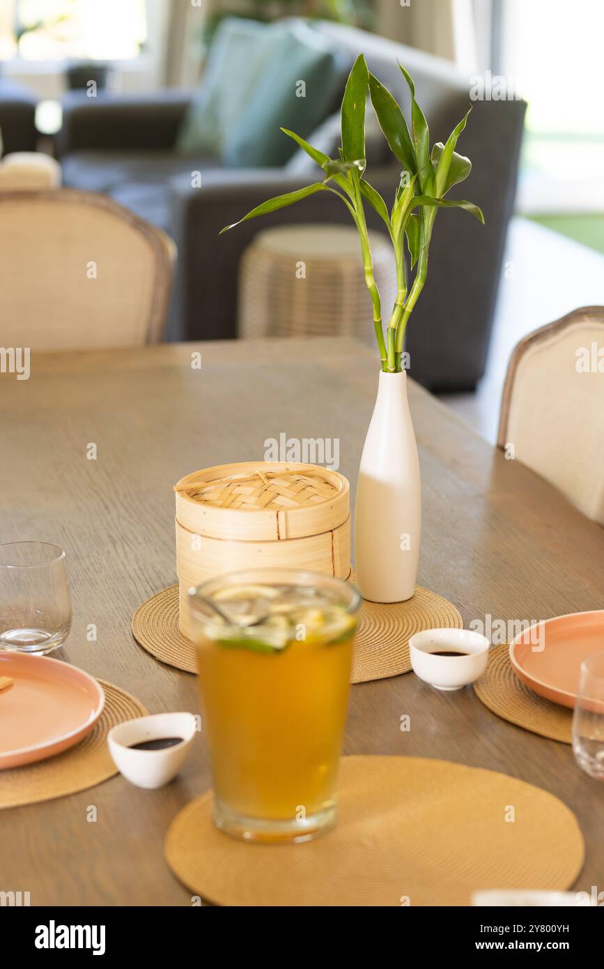 Dining table set with iced tea, bamboo steamer, and small dishes for ...