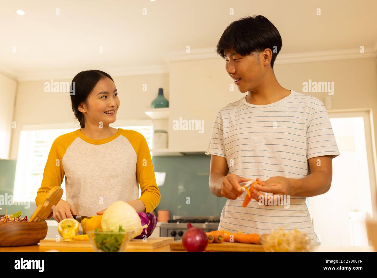Preparing vegetables, smiling asian brother and sister cooking together ...