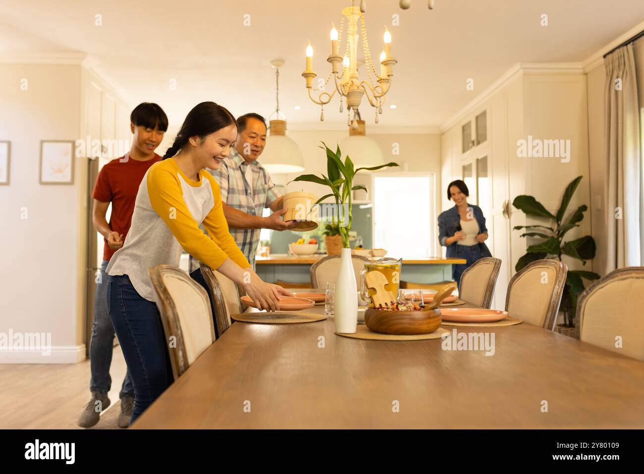 Setting dining table, multiracial family preparing for meal together in ...