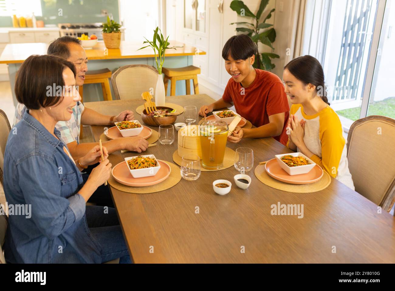 Multiracial family enjoying meal together at dining table, smiling and ...