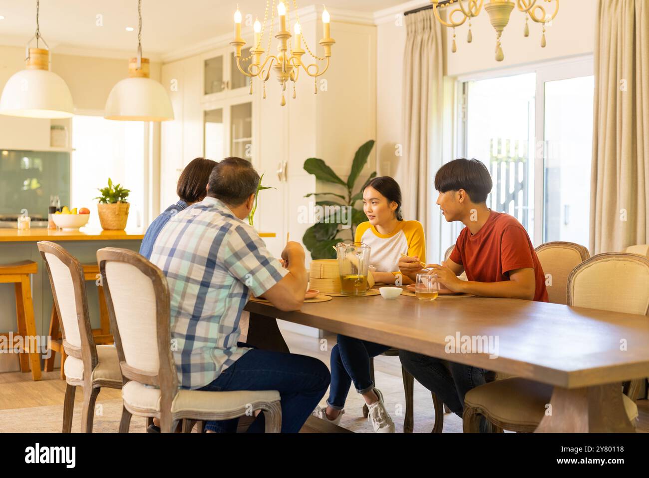 At home, asian family enjoying meal together, sitting at dining table ...