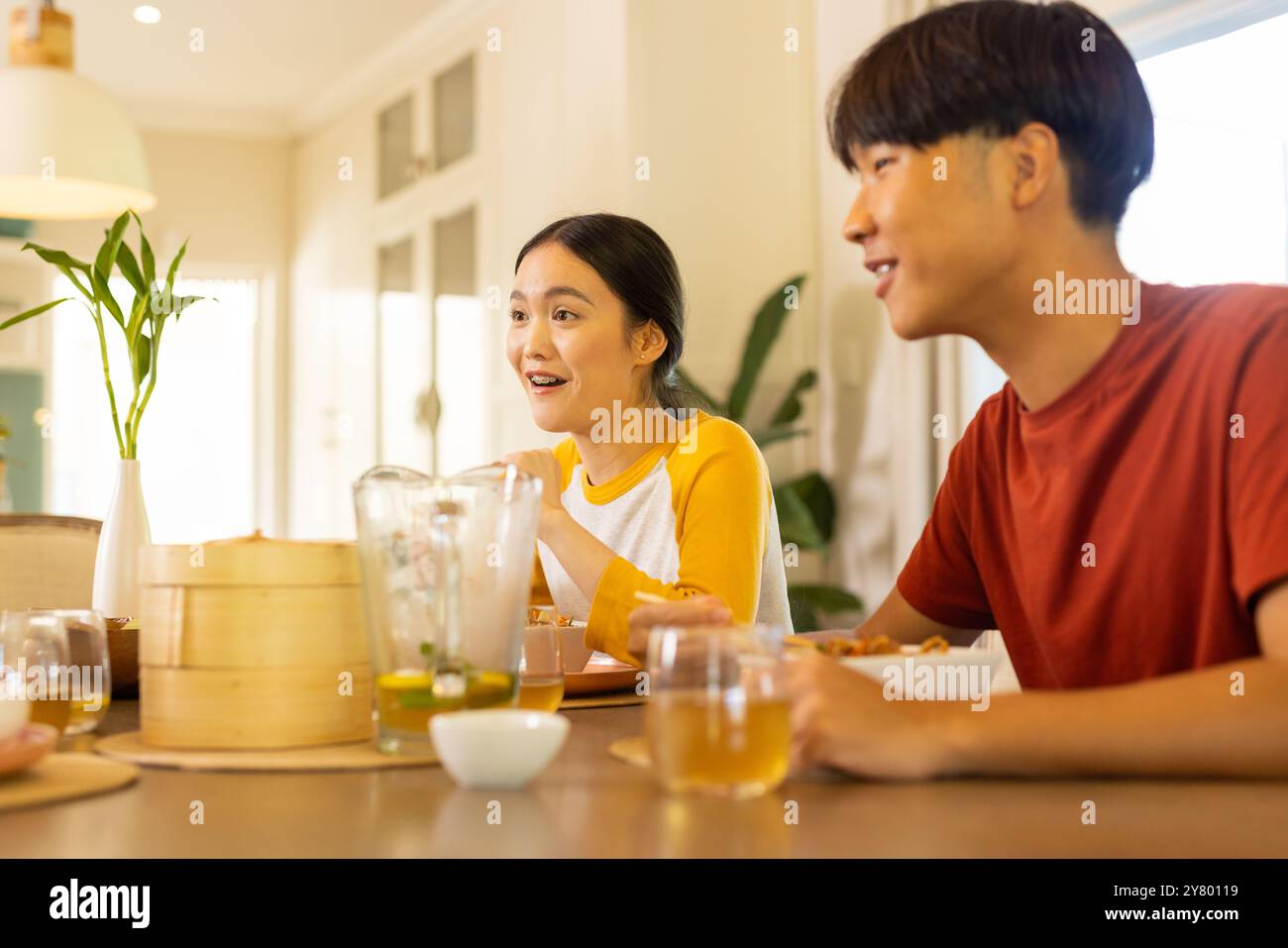 At home, Enjoying family meal, young asian brother and sister smiling ...