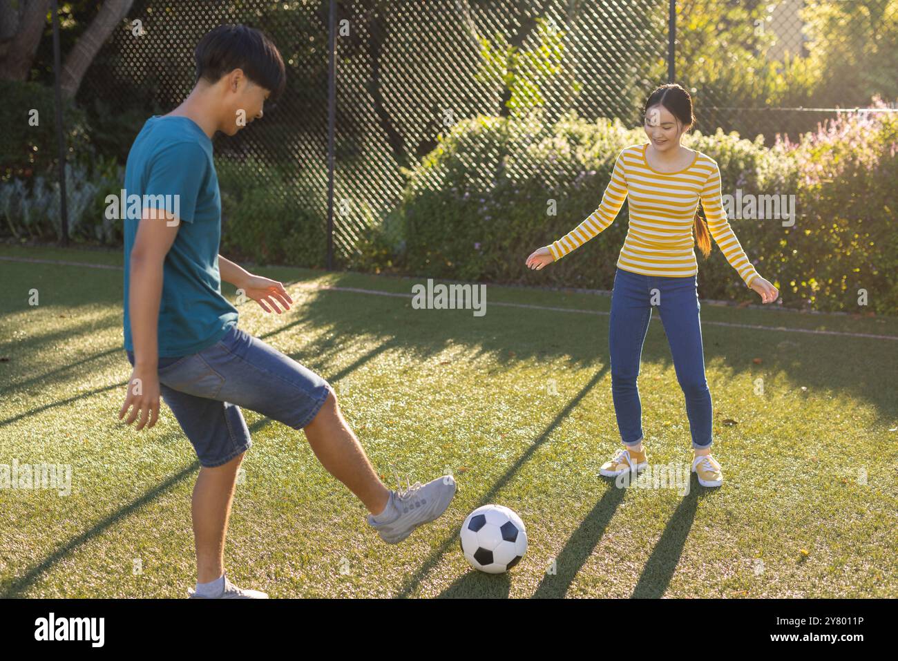 Playing soccer together, young asian brother and sister enjoying ...