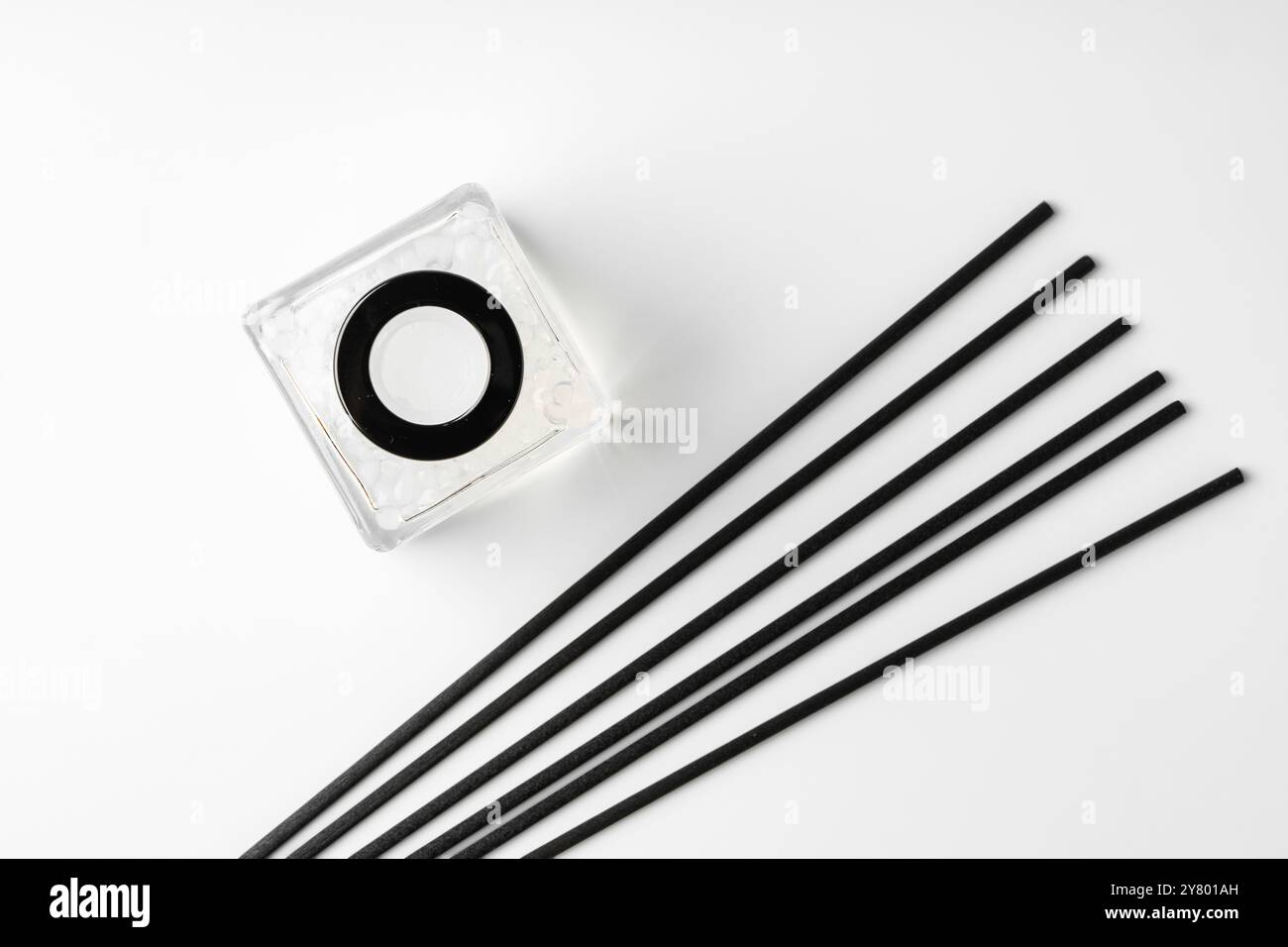 A minimalist display of essential oil and black diffuser sticks on a ...