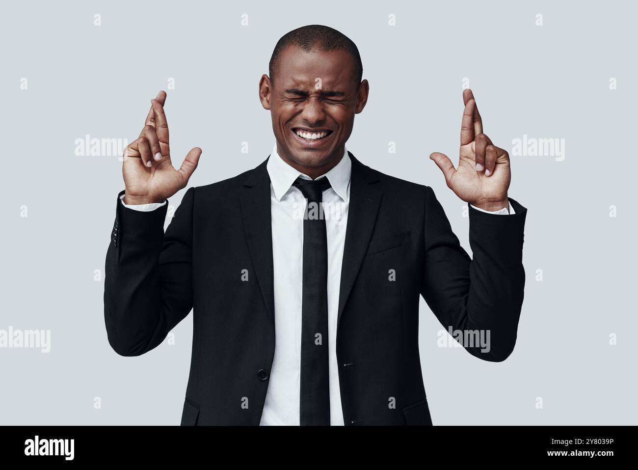 Hoping for the best. Handsome young African man in formalwear keeping ...