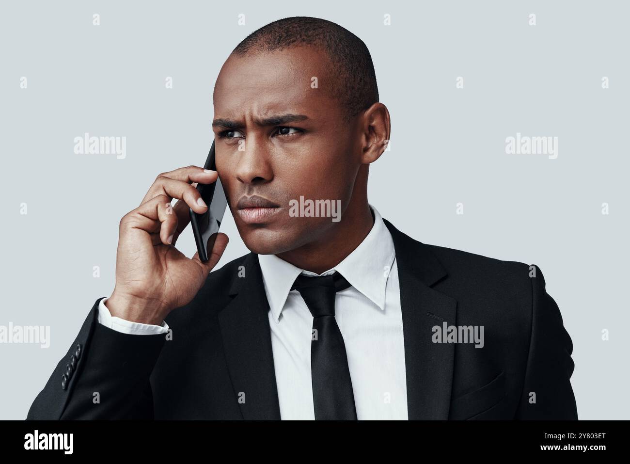 Full concentration. Thoughtful young African man in formalwear talking ...