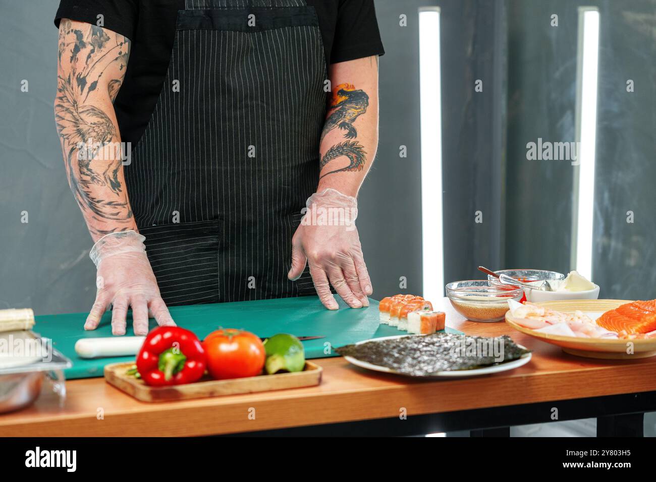 A chef prepares sushi rolls with colorful ingredients on a kitchen ...